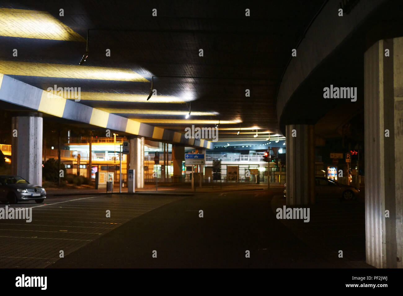 The curve of a bridge underpass at night and in the dark with a parking ...