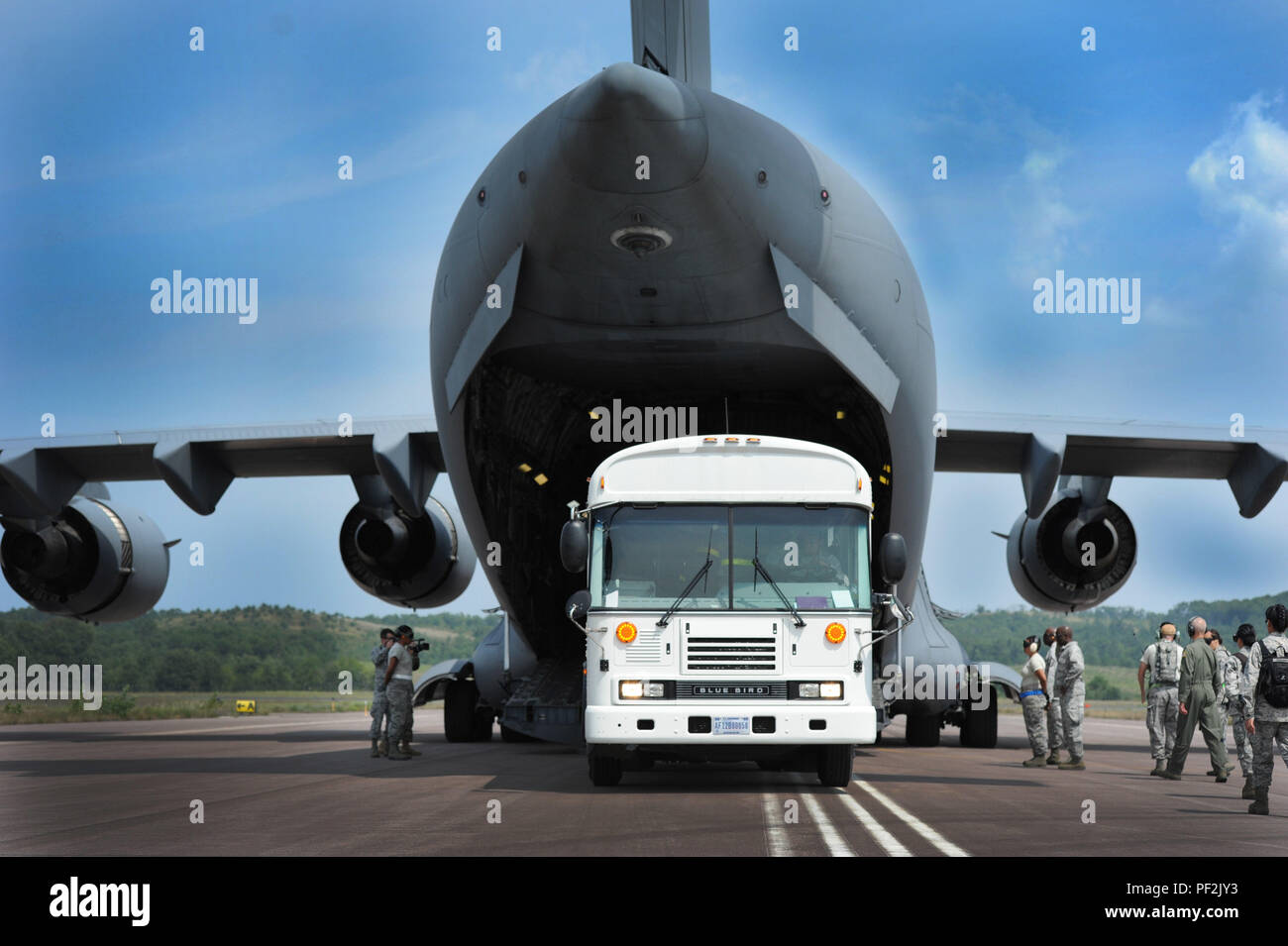 A white bus is parked near a C-17 Globemaster III aircraft assigned to ...
