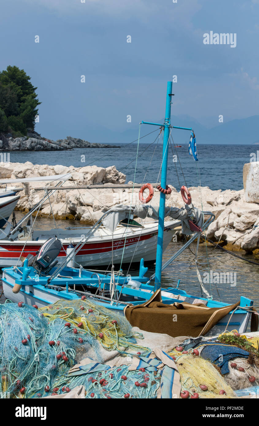 colourful greek fishing boats and nets in the harbour at Kassiopi on ...