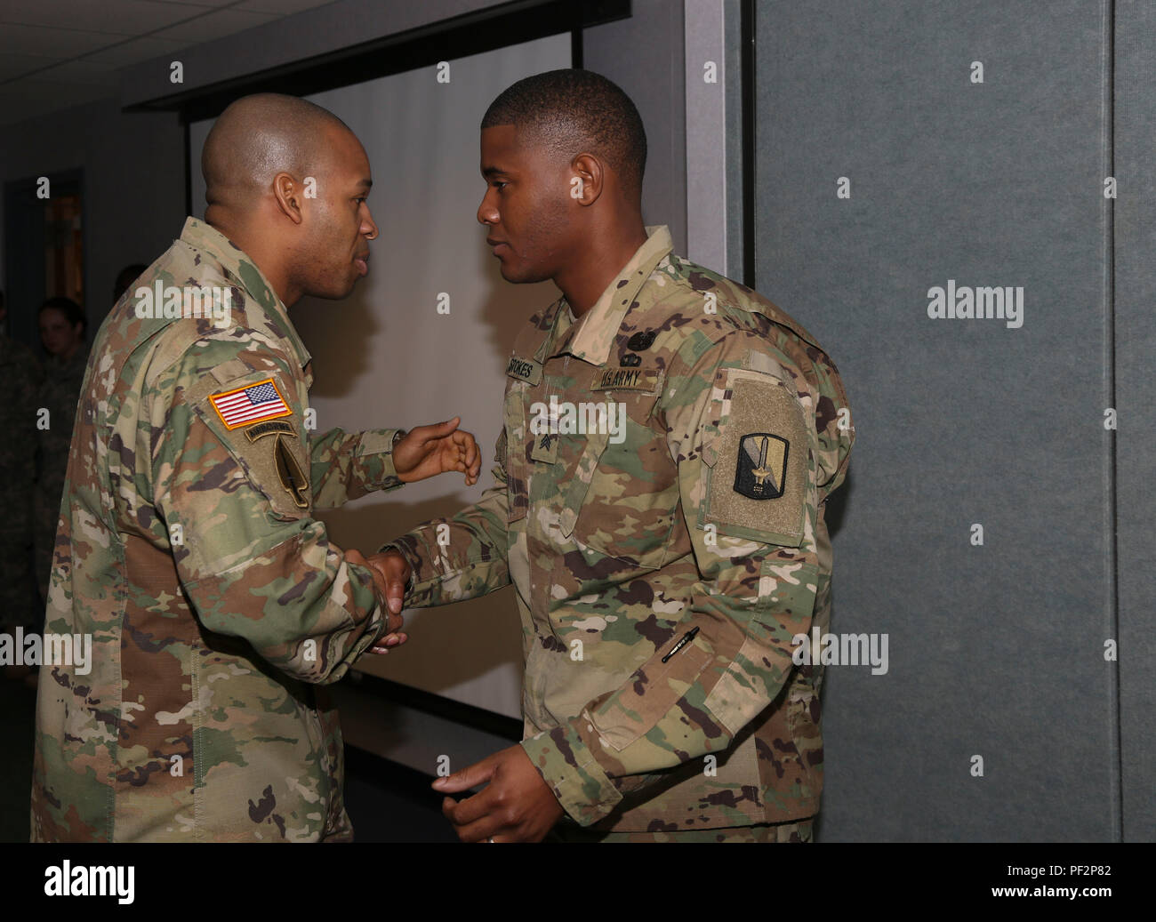 U.S. Army 1st Sgt. Endesha Johnson, shakes hands with Sgt. Sha'quille Stokes, both assigned to ...