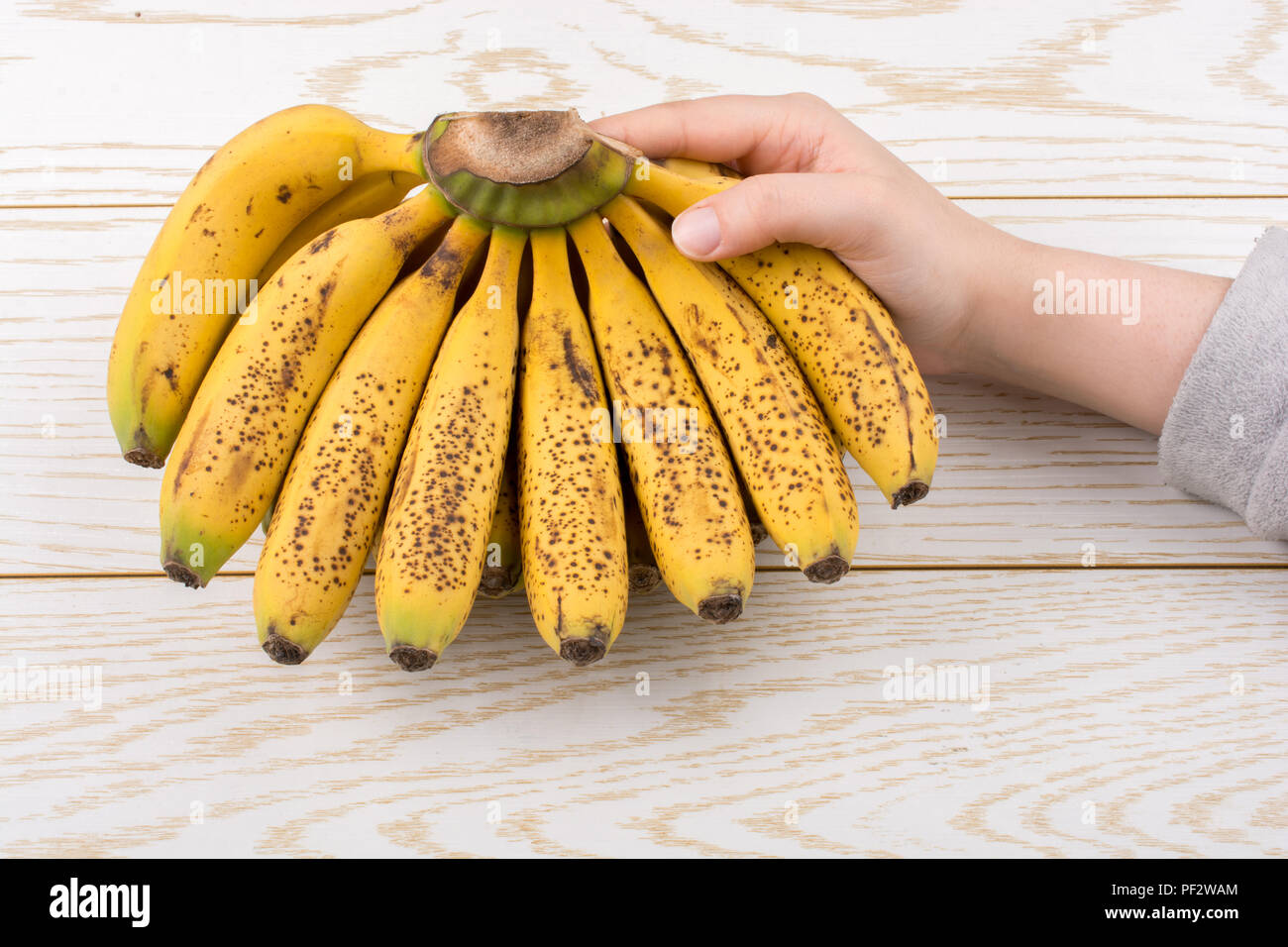 Hand holding bunch of freckled bananas on a wooden texture Stock Photo ...