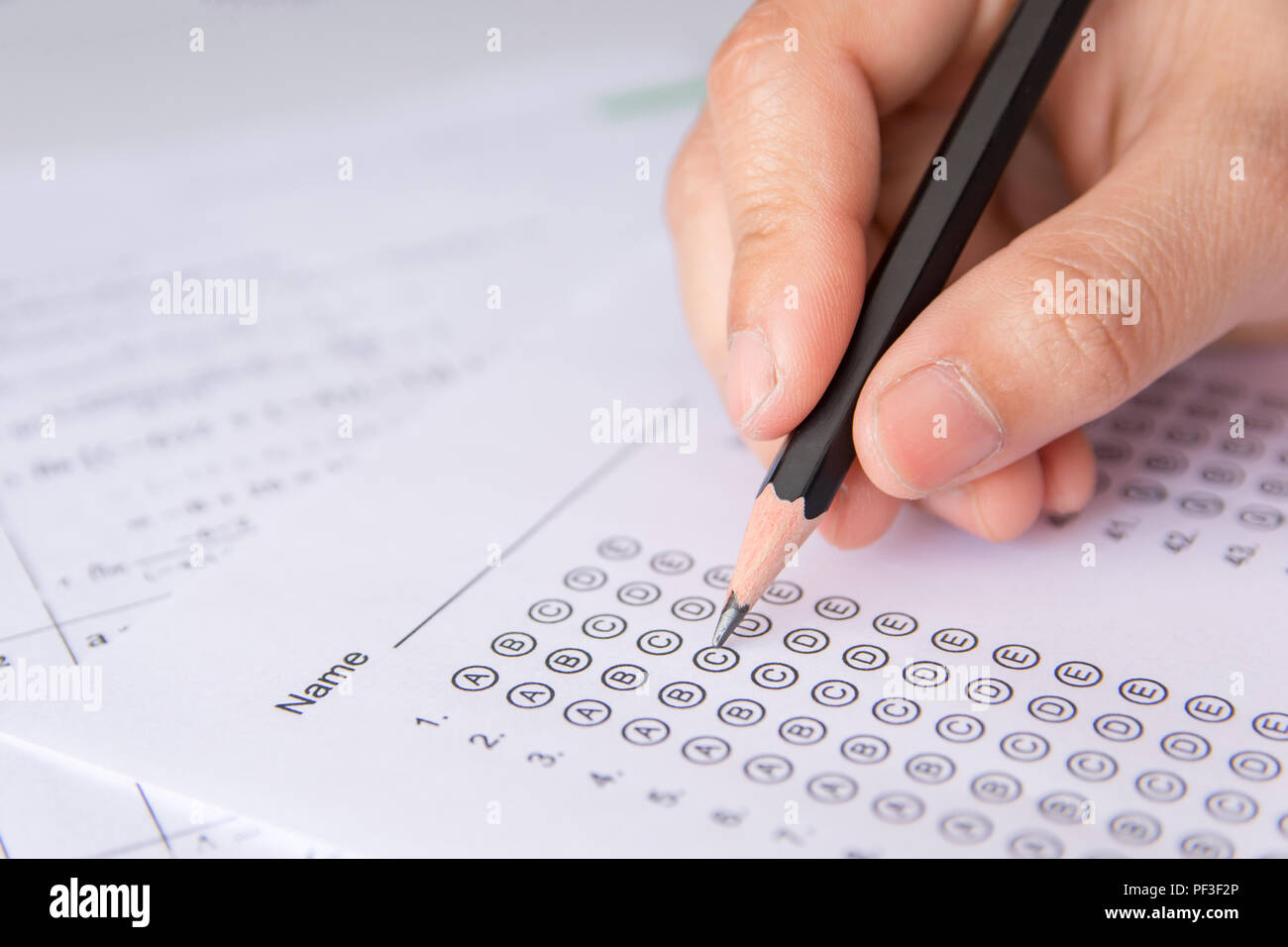 Students hand holding pencil writing selected choice on answer sheets ...