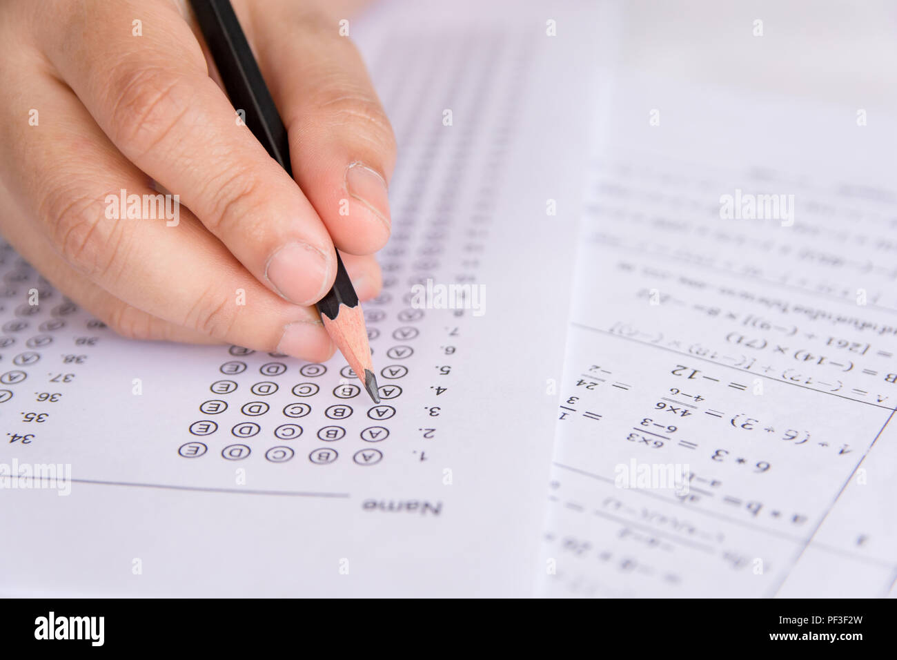 Students hand holding pencil writing selected choice on answer sheets ...