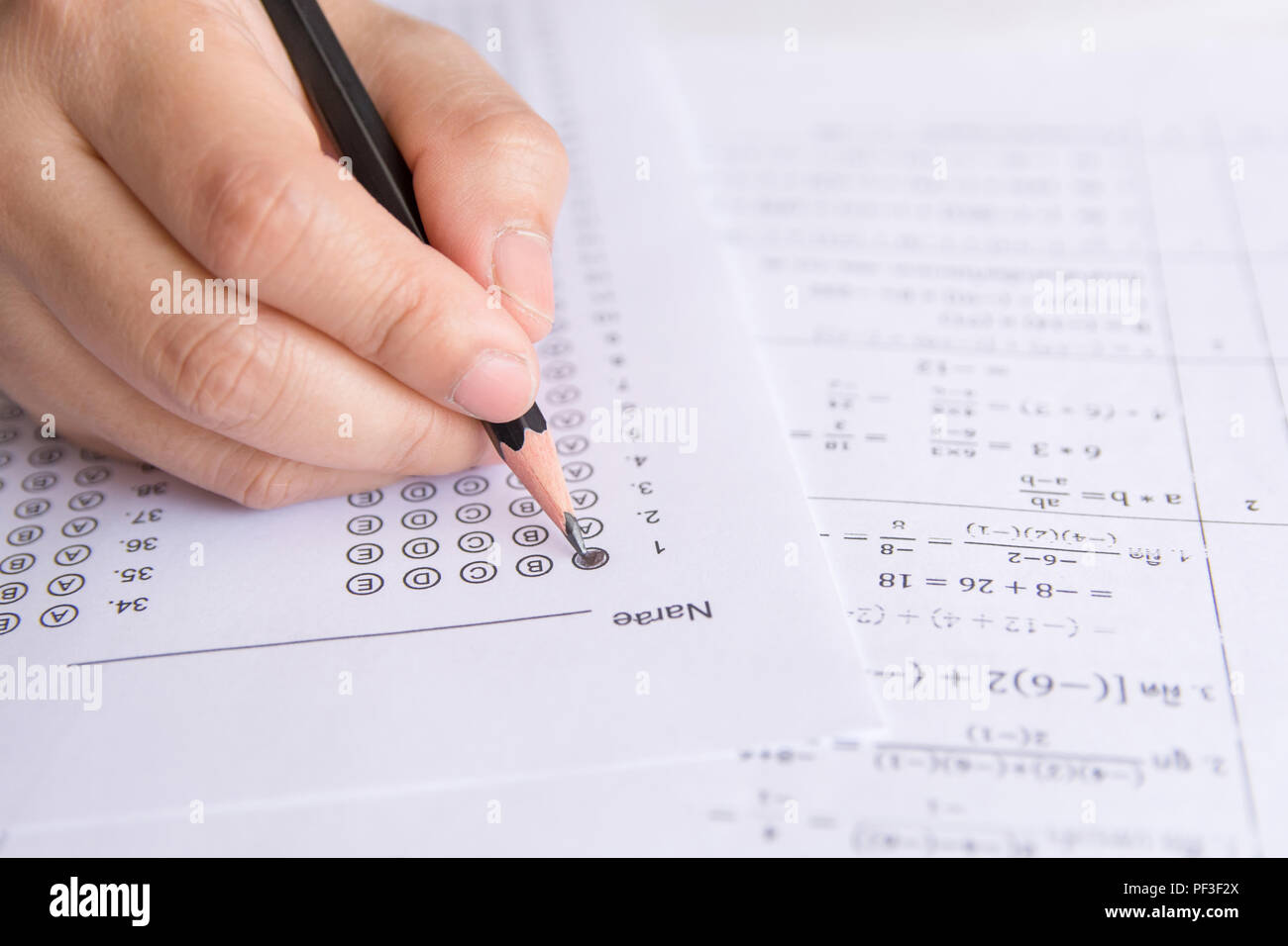 Students hand holding pencil writing selected choice on answer sheets ...