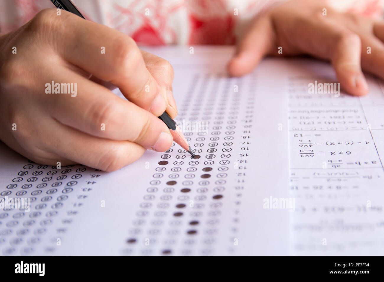 Students hand holding pencil writing selected choice on answer sheets ...