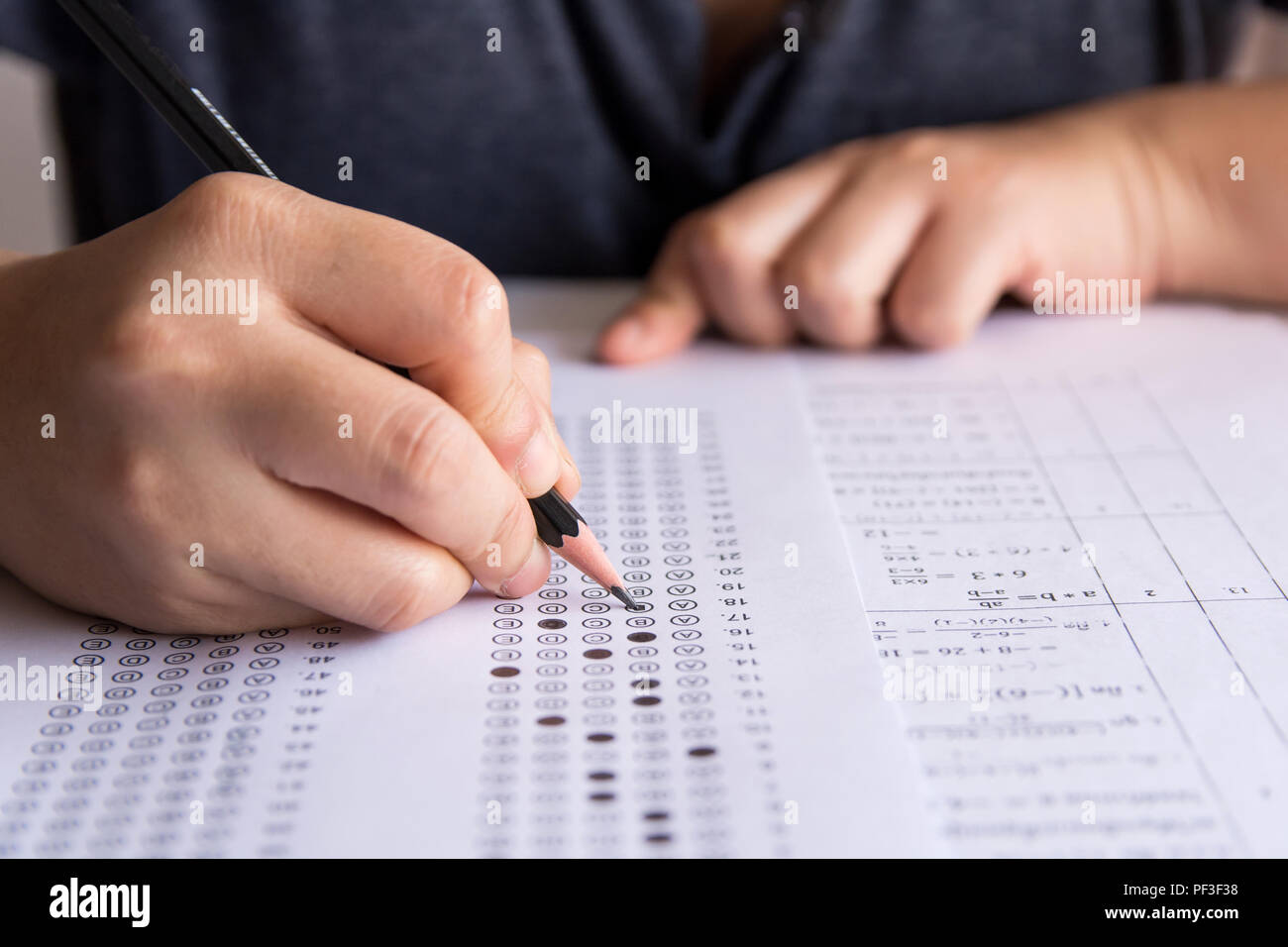 Students hand holding pencil writing selected choice on answer sheets ...