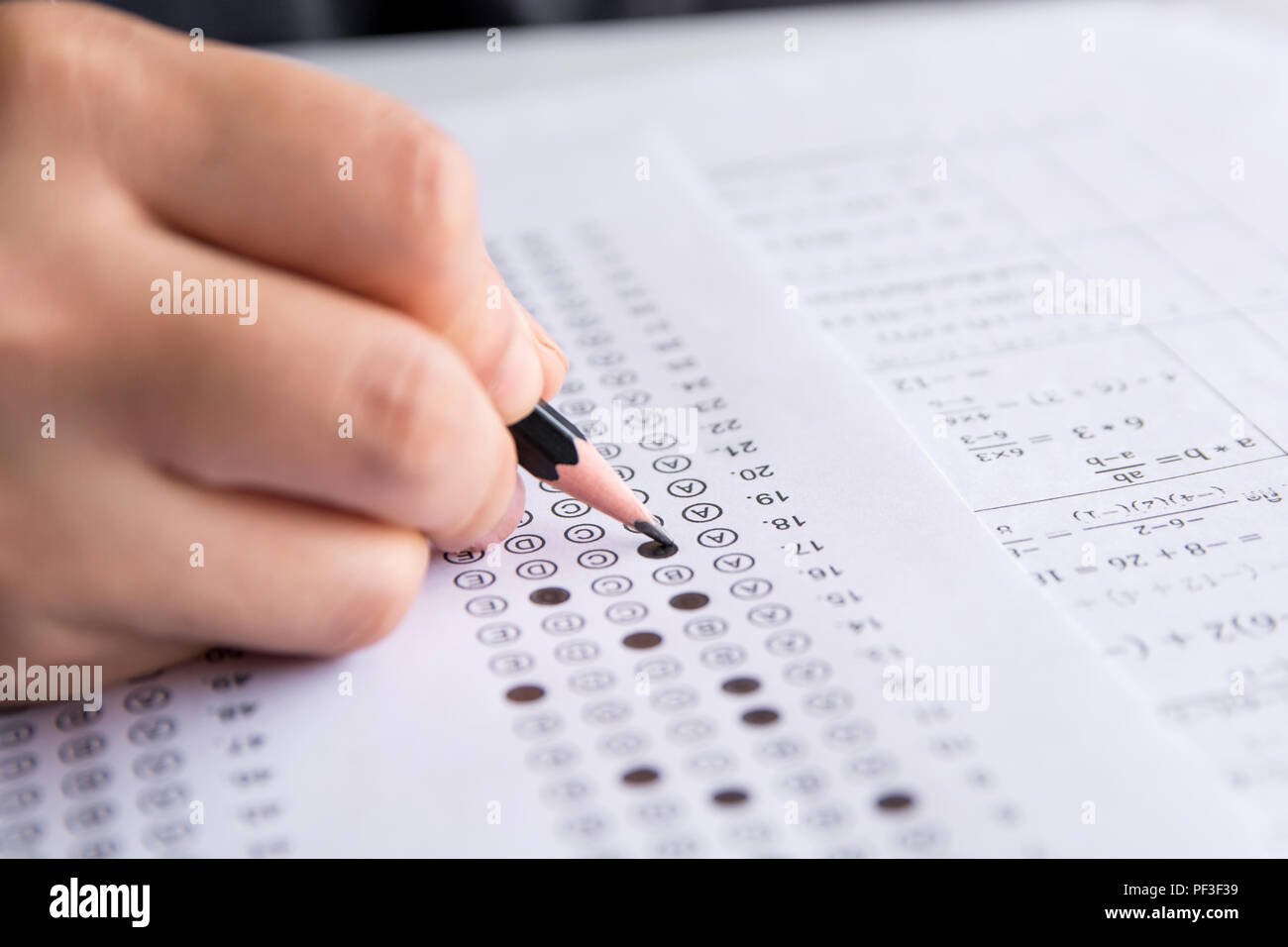 Students hand holding pencil writing selected choice on answer sheets ...
