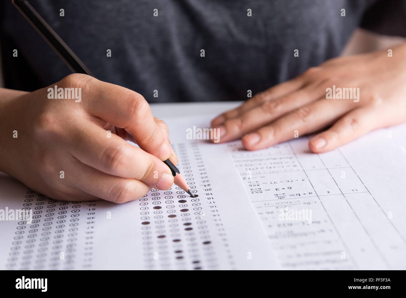 Students hand holding pencil writing selected choice on answer sheets ...