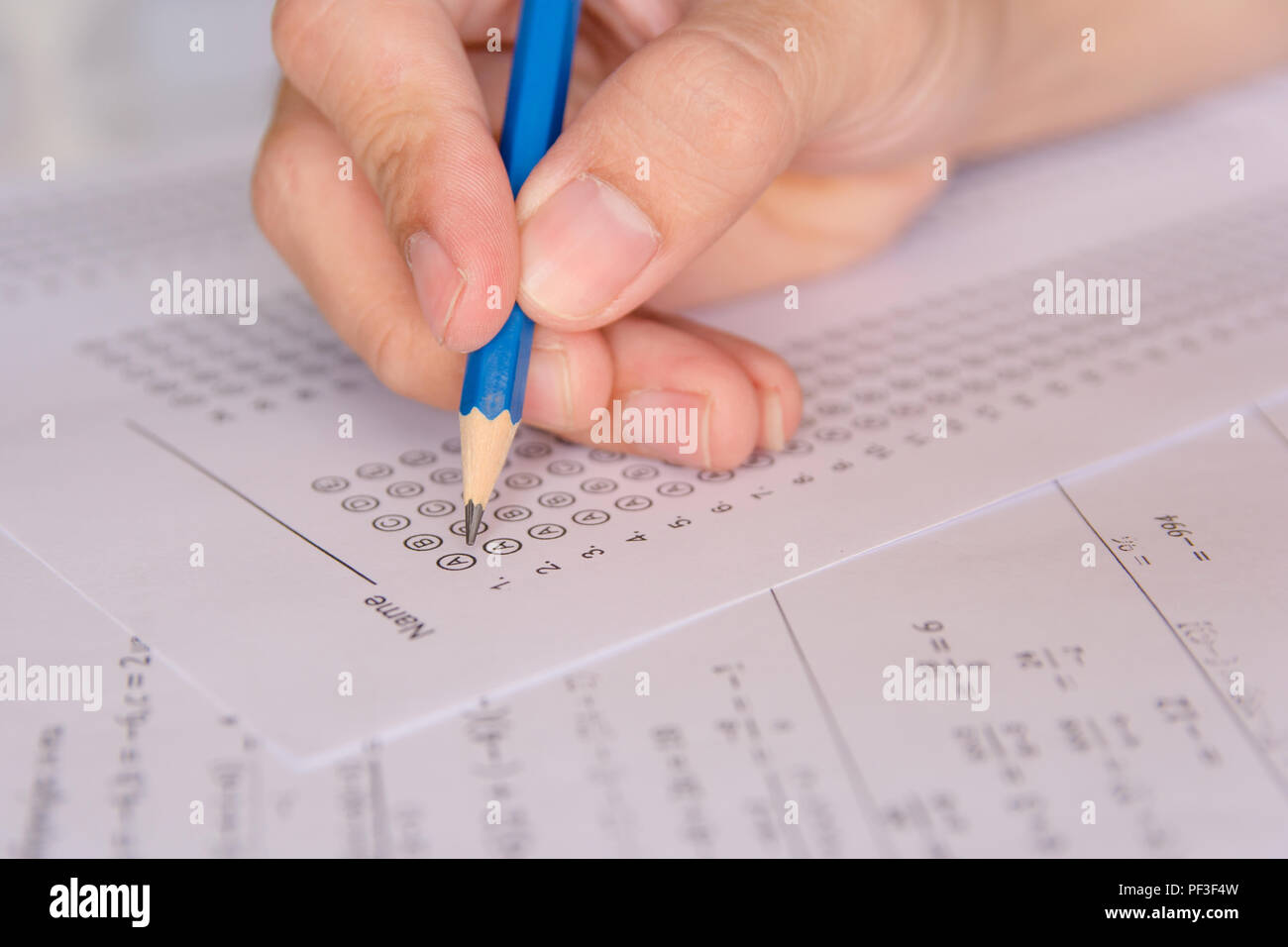 Students hand holding pencil writing selected choice on answer sheets ...
