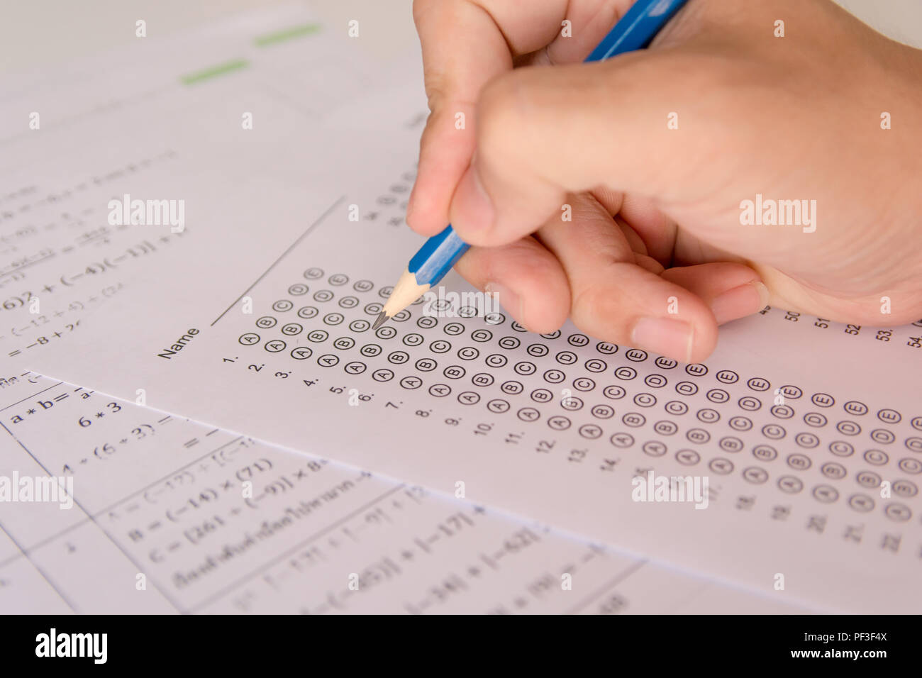 Students hand holding pencil writing selected choice on answer sheets ...