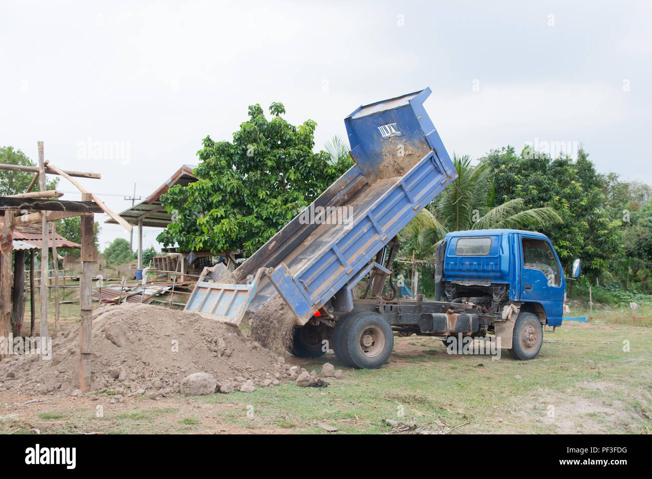 Blue dump truck unloading soil at construction site Stock Photo - Alamy