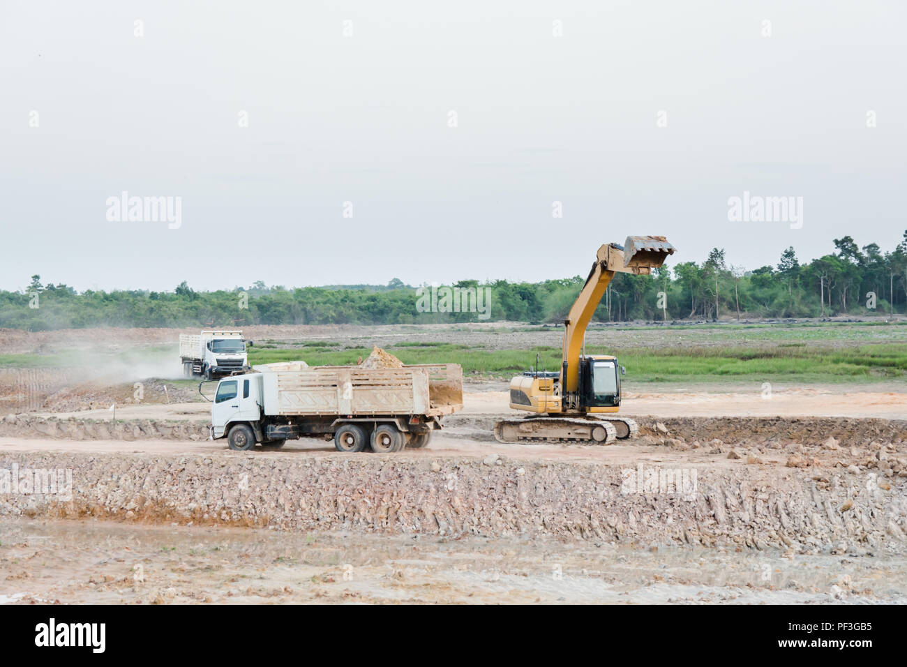 Yellow excavator machine loading soil into a dump truck at construction ...