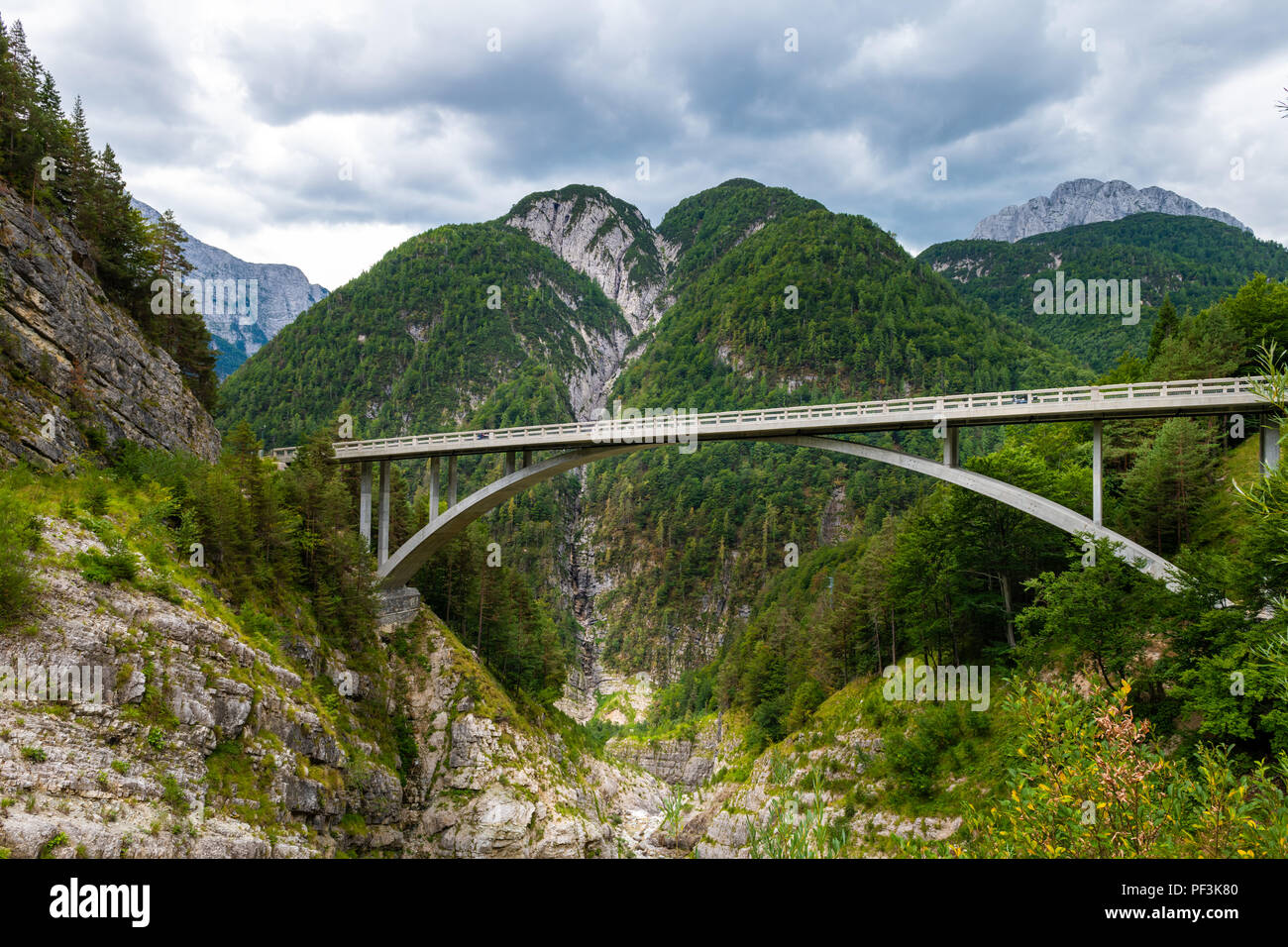 Arched bridge over a mountain river gorge in European Alps with ...