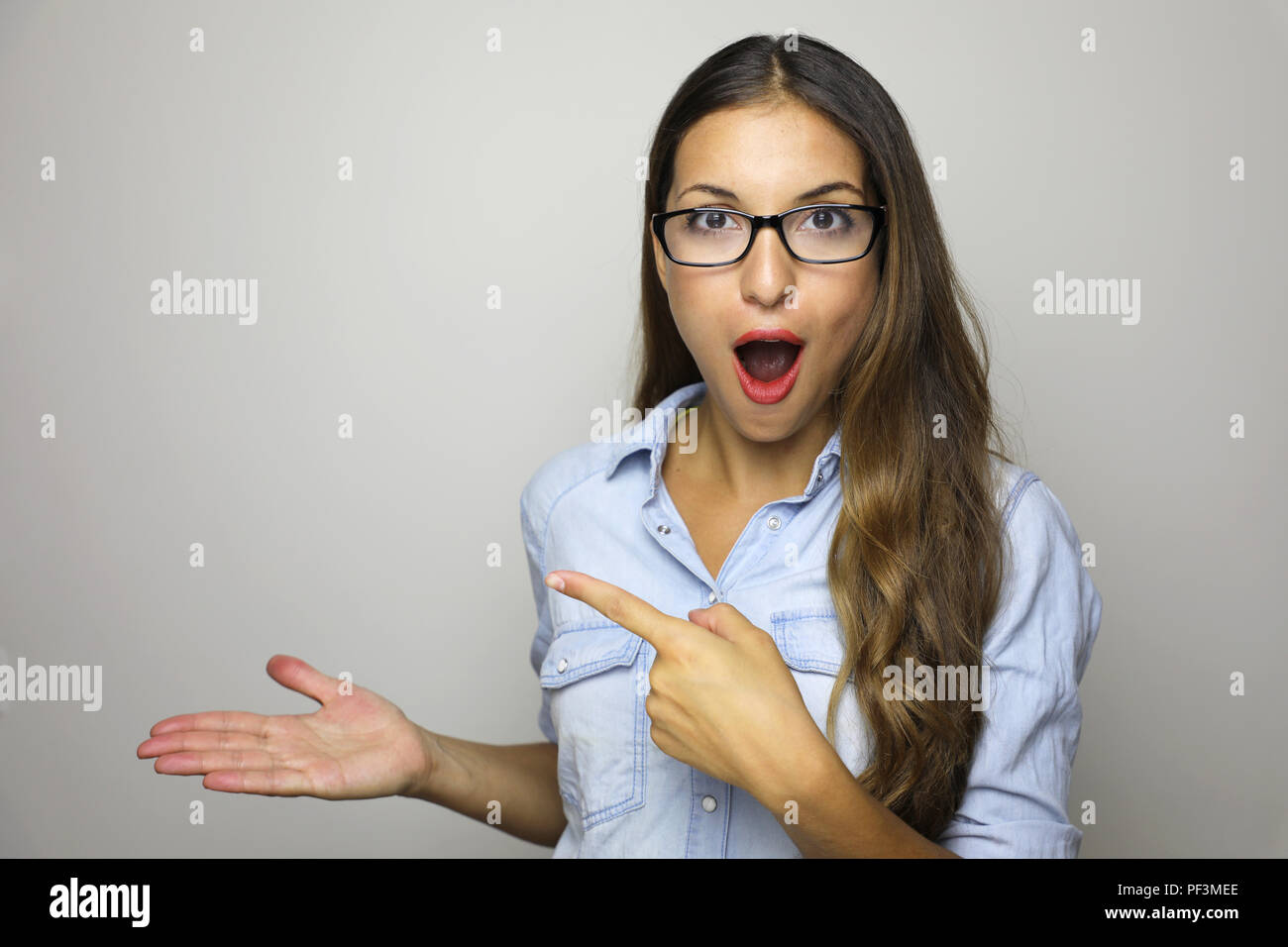 Young woman showing product with open hand palm and pointing finger ...