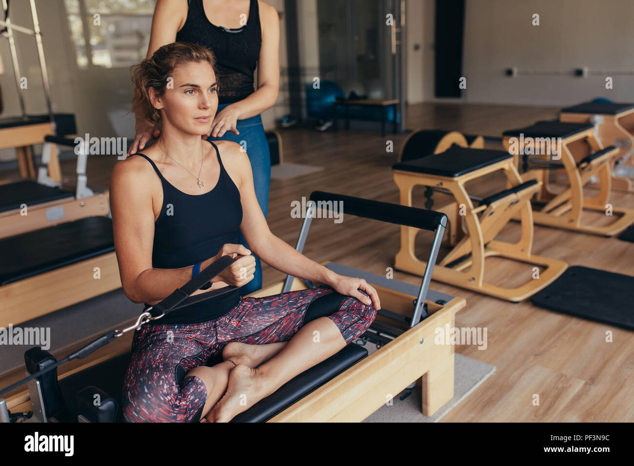 fitness women sitting with legs crossed on a pilates training machine ...