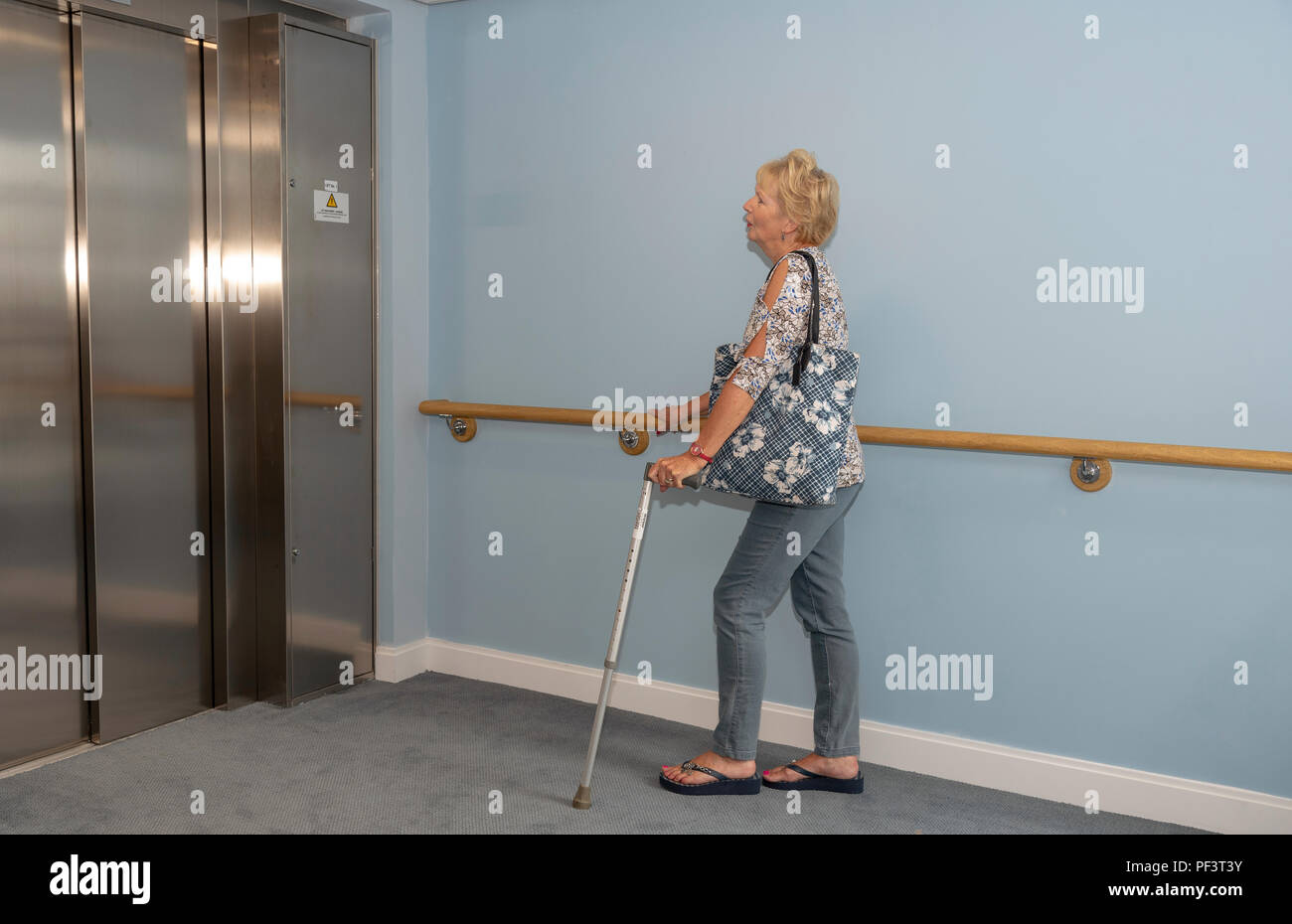 Elderly lady waiting to use a lift between floors Stock Photo - Alamy