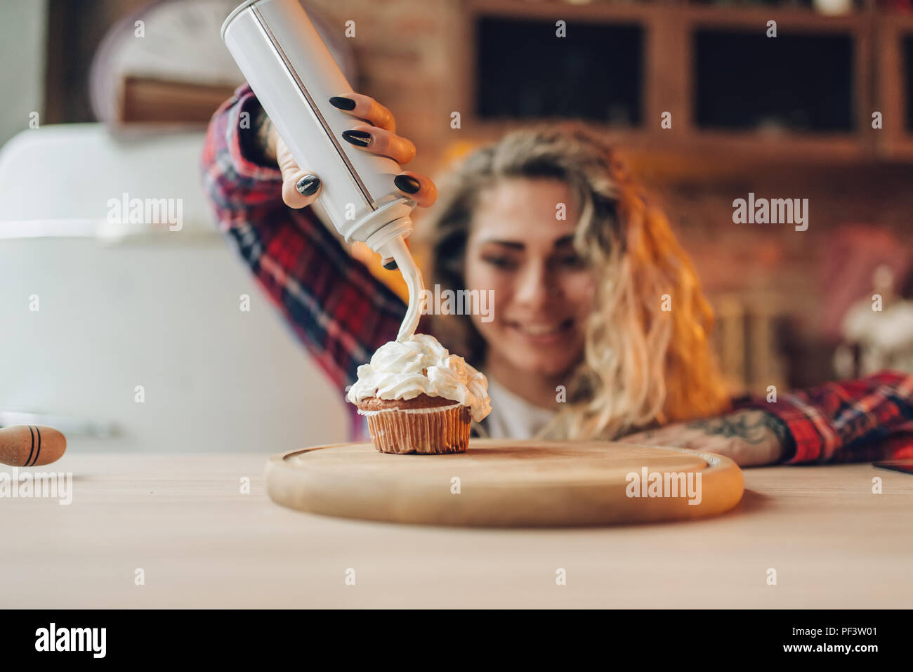 Housewife In Apron Covers Sweet Dessert With Cream Kitchen Interior On