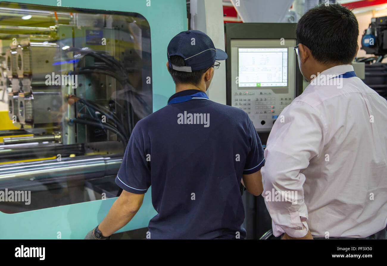 worker operate industrial plastic injection molding press machine for ...