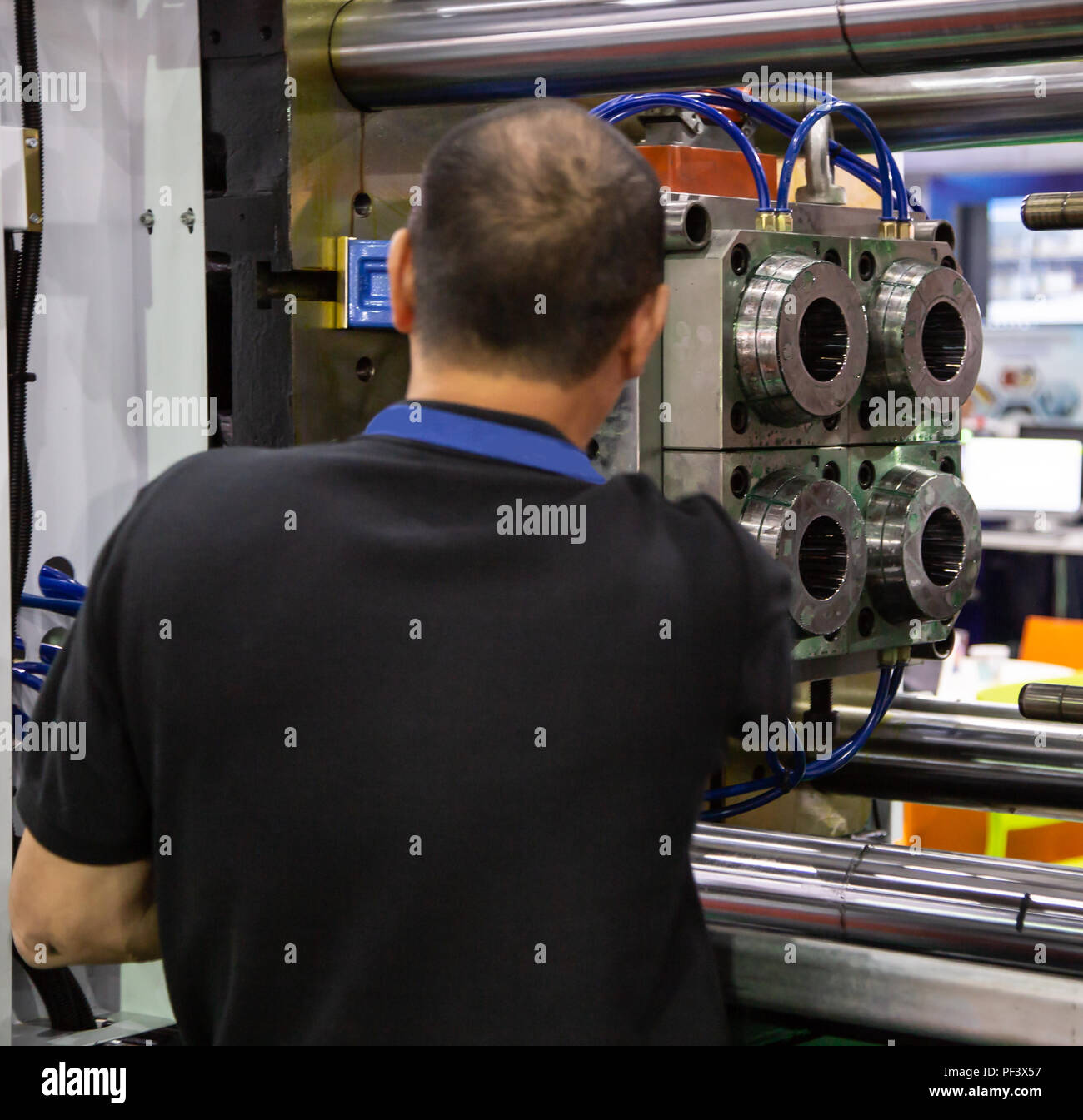worker setting up industrial plastic injection molding press machine ...