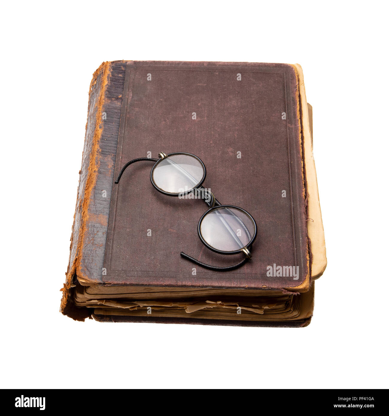 Very old and worn book with antique round eyeglasses. Isolated on white ...
