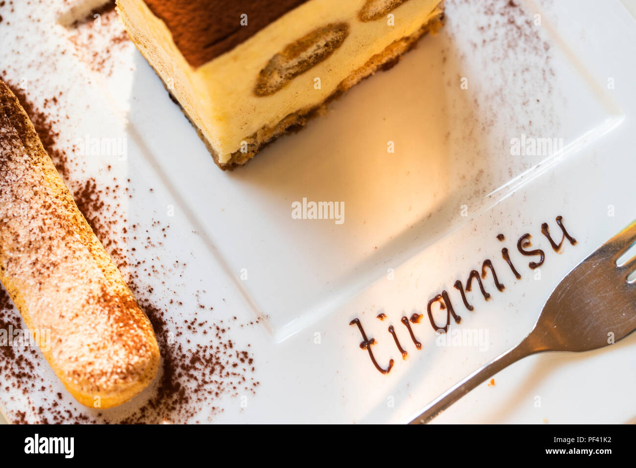 Tiramisu, traditional Italian dessert on a white plate. Close up Stock ...