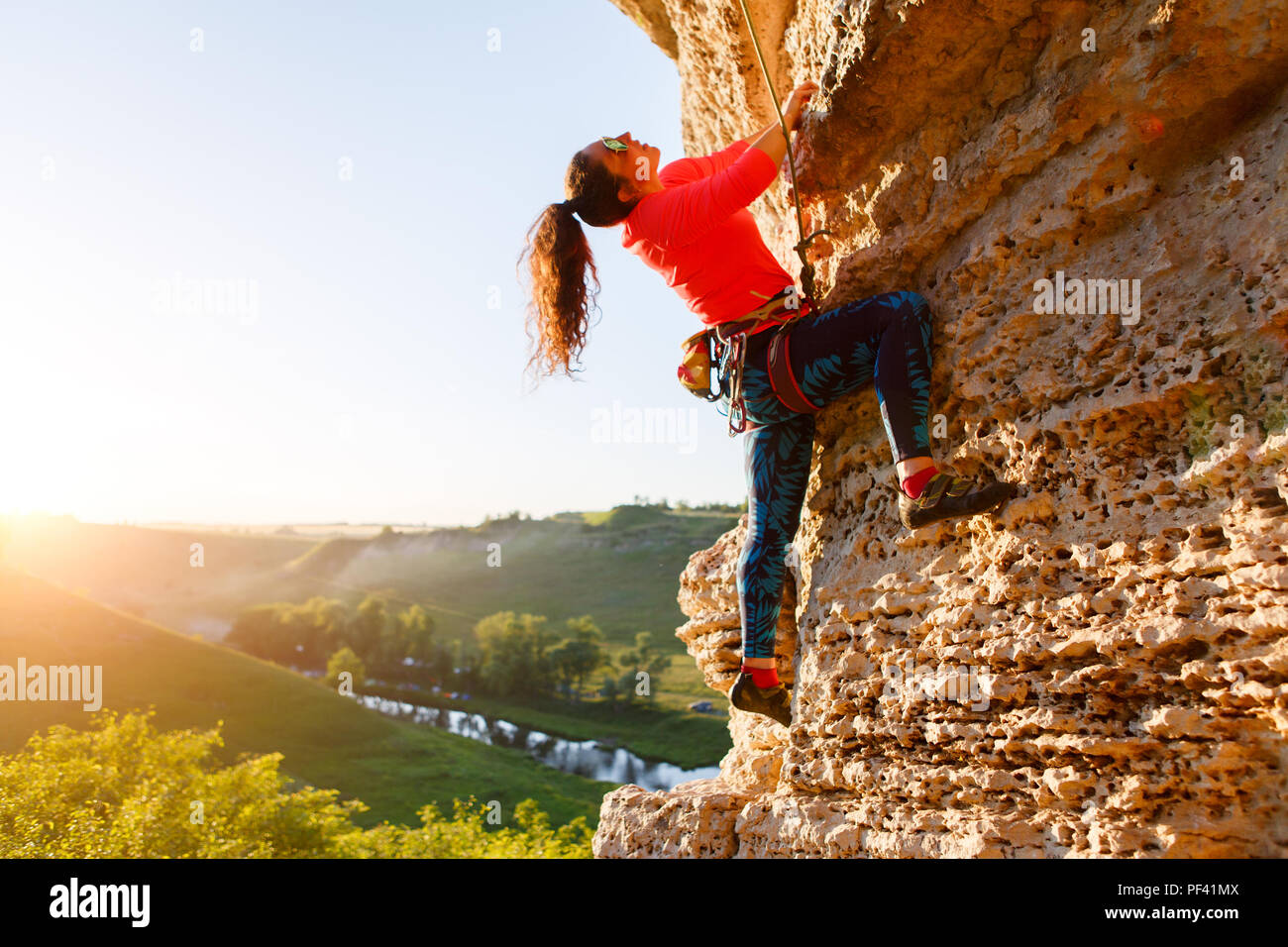 Image of curly-haired female tourist clambering over rock Stock Photo ...