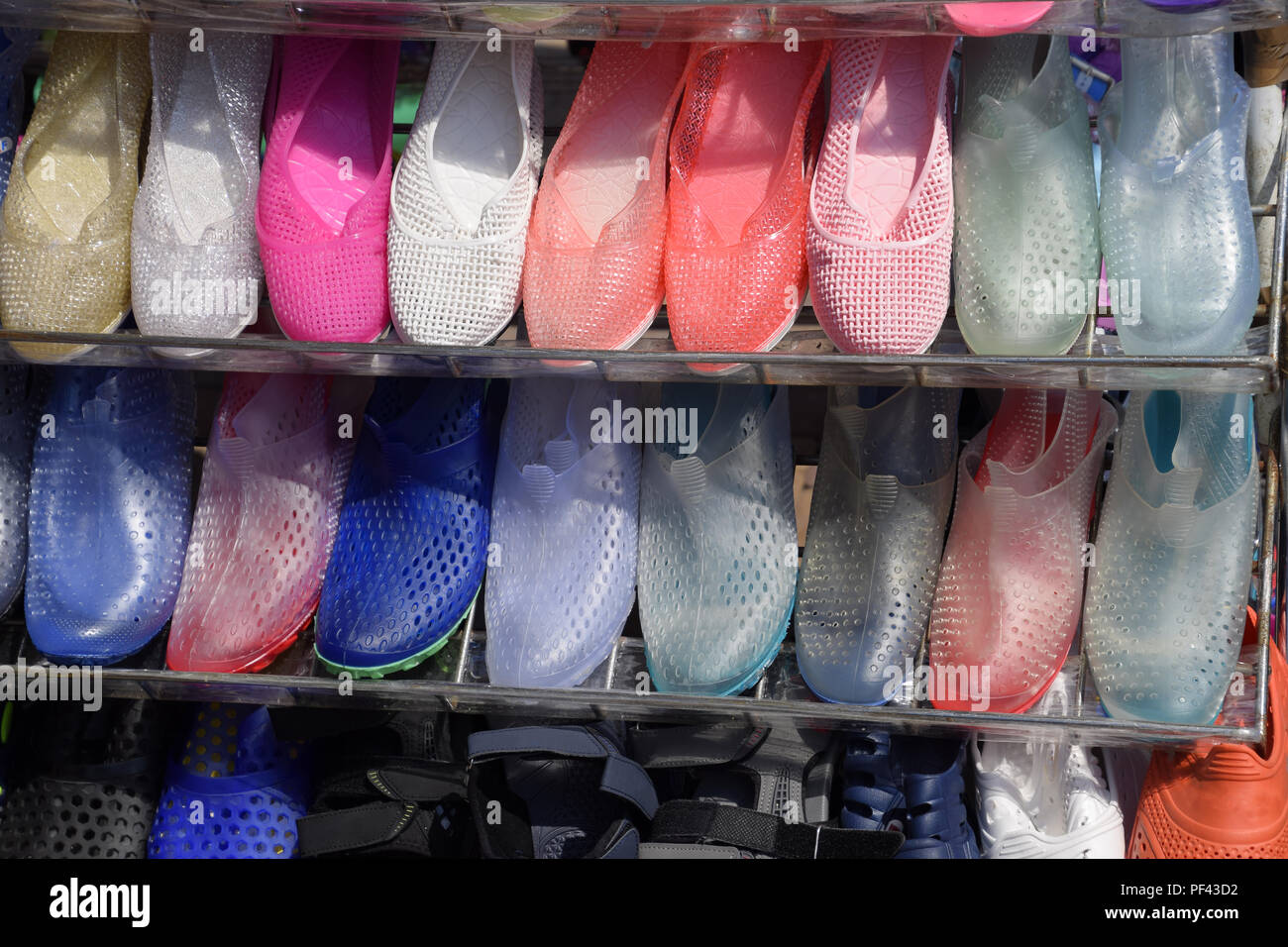 Rubber and silicone sandals and sneakers on the shoe shelf in the ...