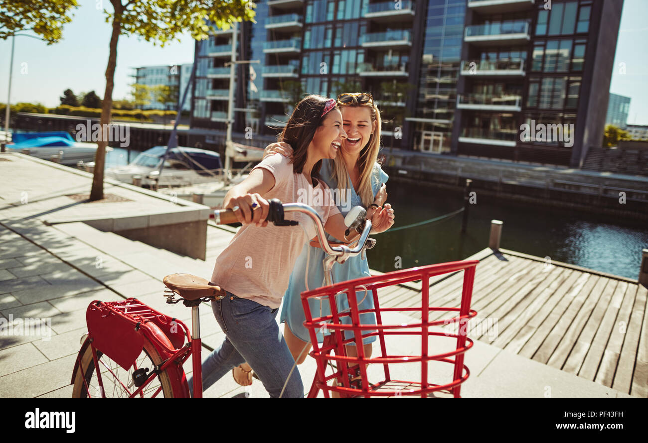 Two laughing best friends walking together through the city with their ...
