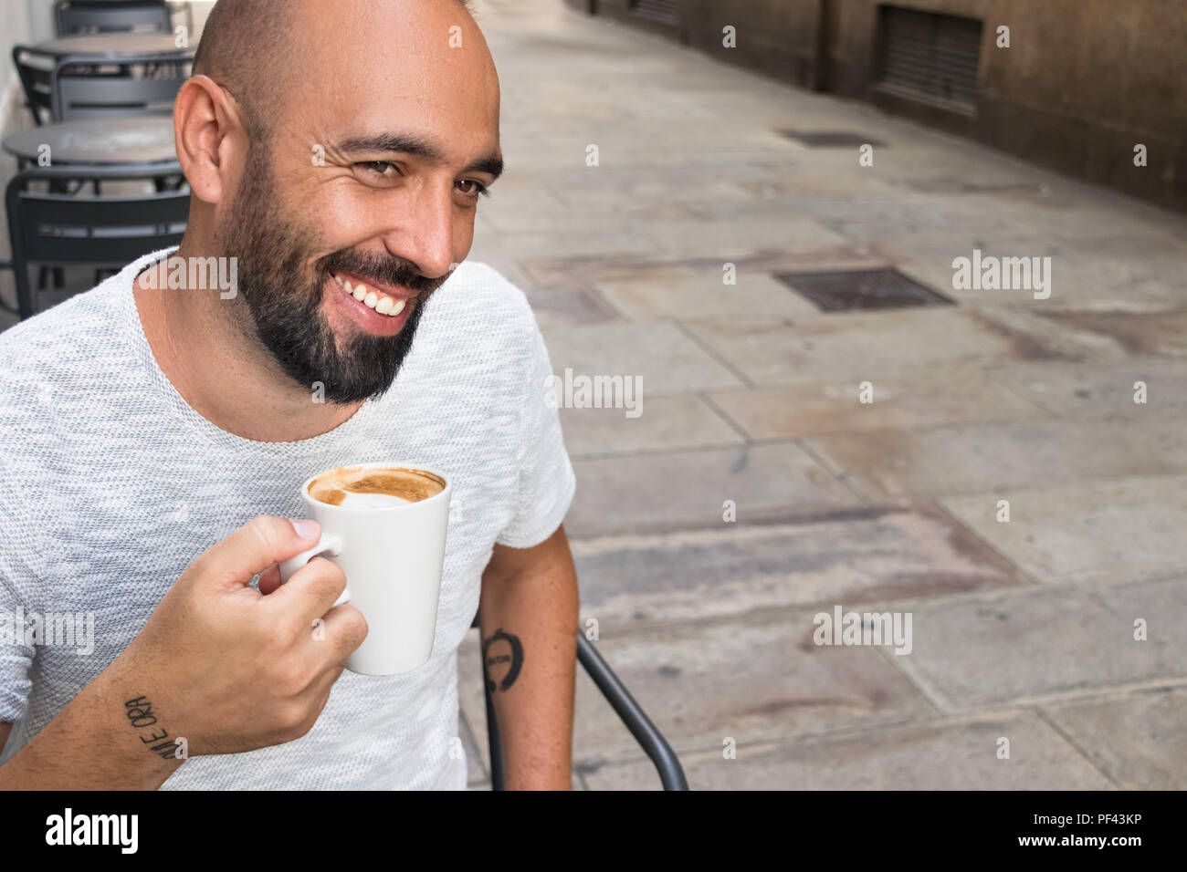 Portrait of a spanish man with beard having coffee sitting outdoors ...