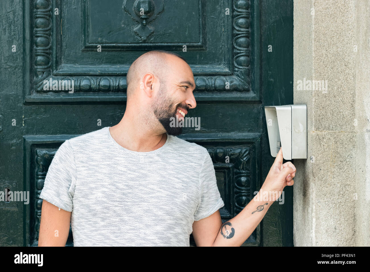 Portrait of a spanish man with beard ringing the doorbell in the street ...