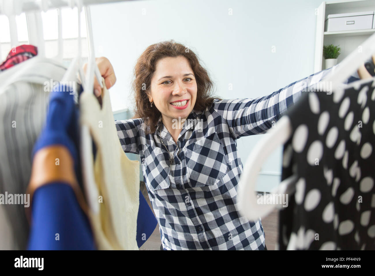 Wardrobe, clothes, people concept - woman choosing clothes to wear in ...