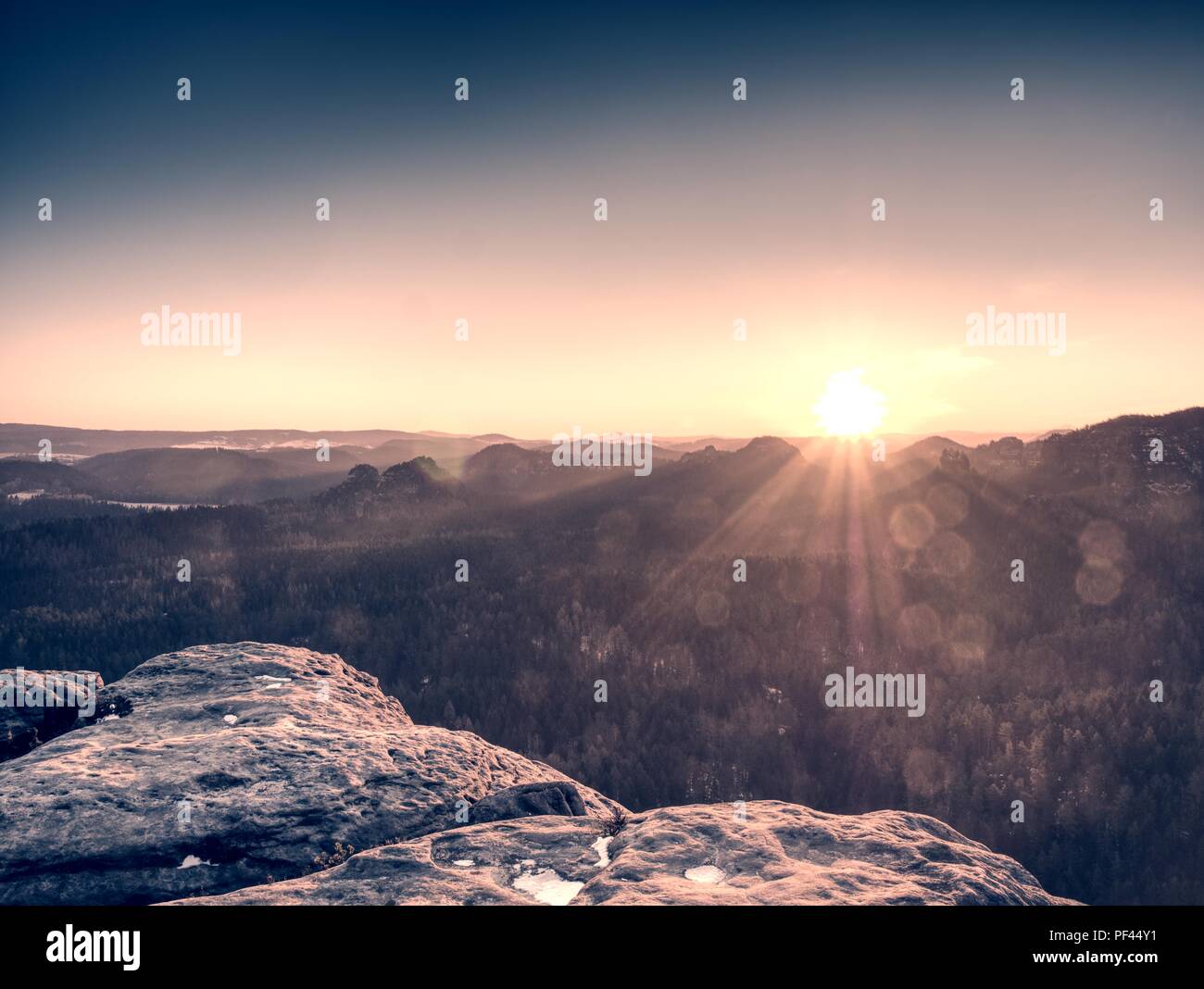Exposed sandstone cliff above deep misty valley at beginning of hot ...