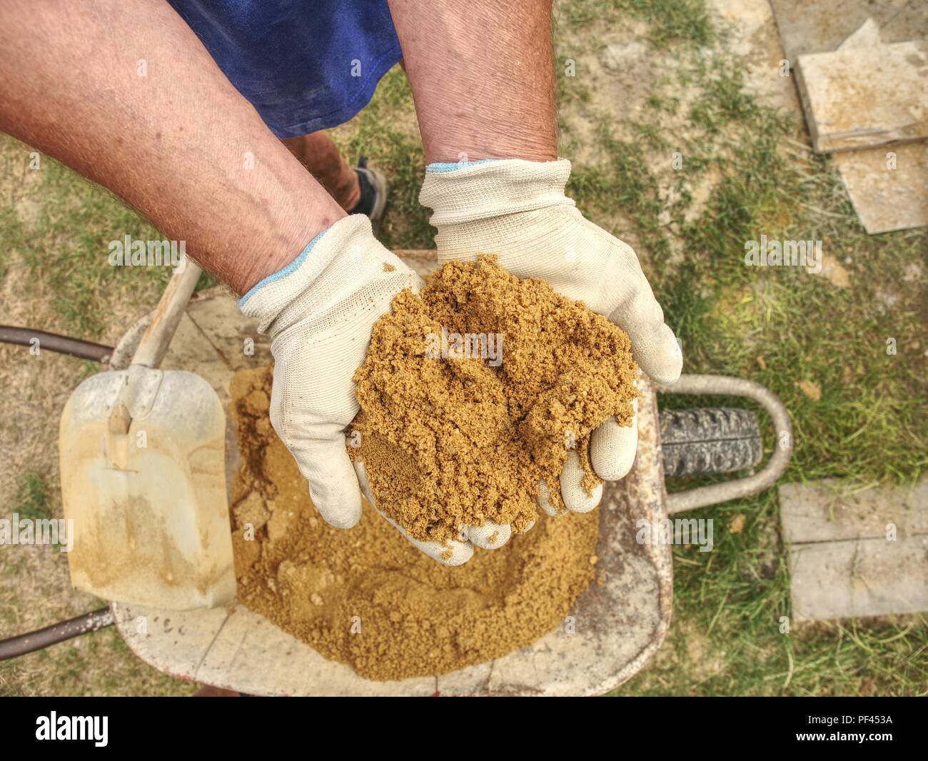 Worker hands in gloves holds sand. Wet yellow sand for building ...