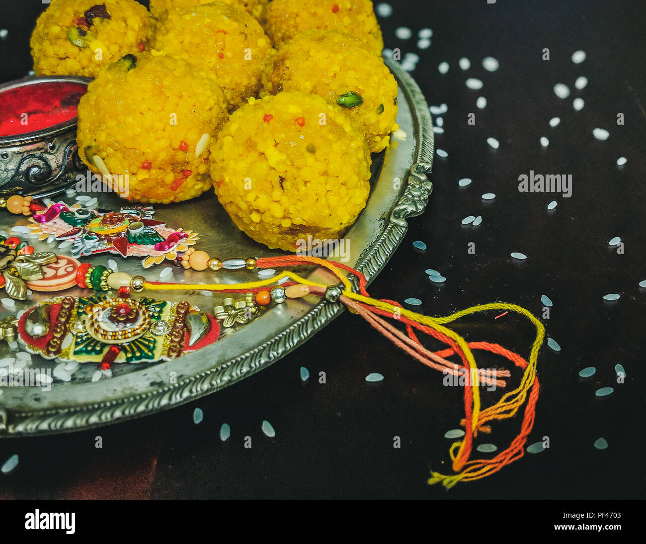 Rakhi with rice grains, kumkum and sweets on decorative plate and ...