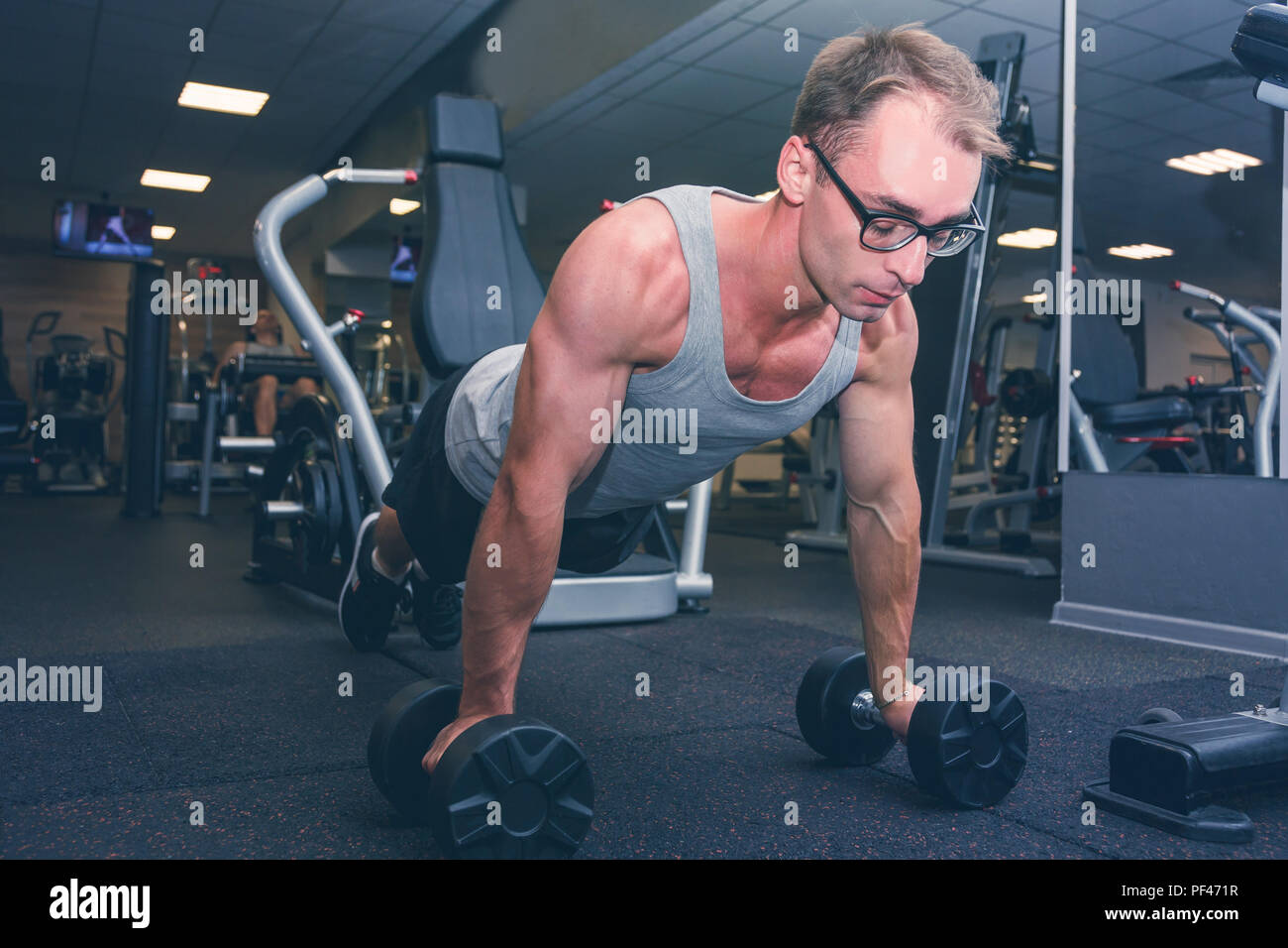 Strong man doing push-ups exercises on dumbbells Stock Photo - Alamy