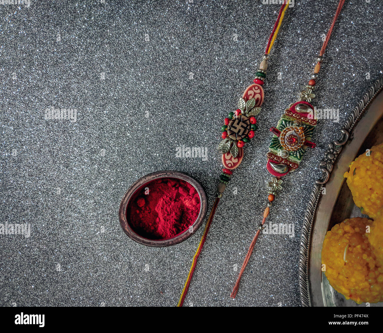 Rakhi with rice grains, kumkum and sweets on decorative plate and ...