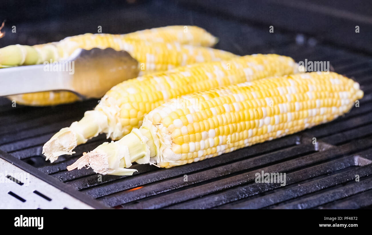 Step by step. Grilling organic corn on outdoor gas grill Stock Photo ...