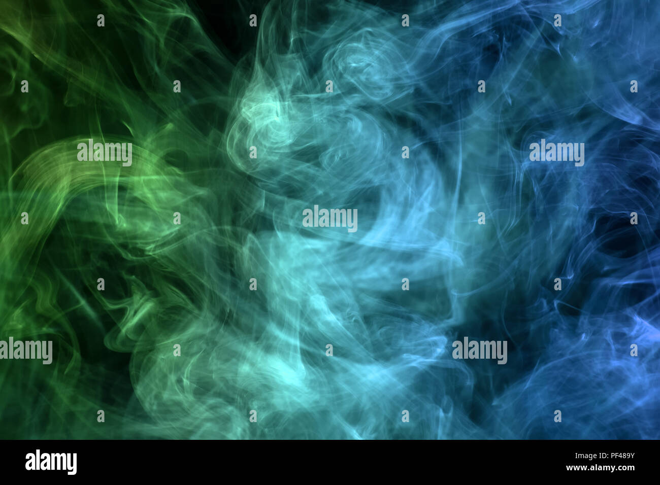 Thick colorful blue and green smoke on a black isolated background ...