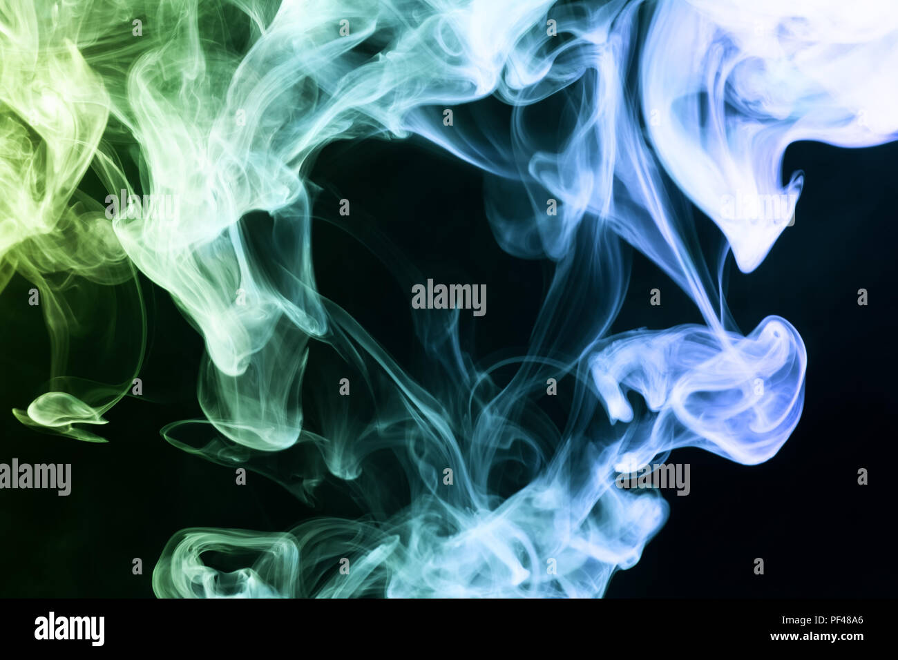 Thick colorful blue and green smoke on a black isolated background ...