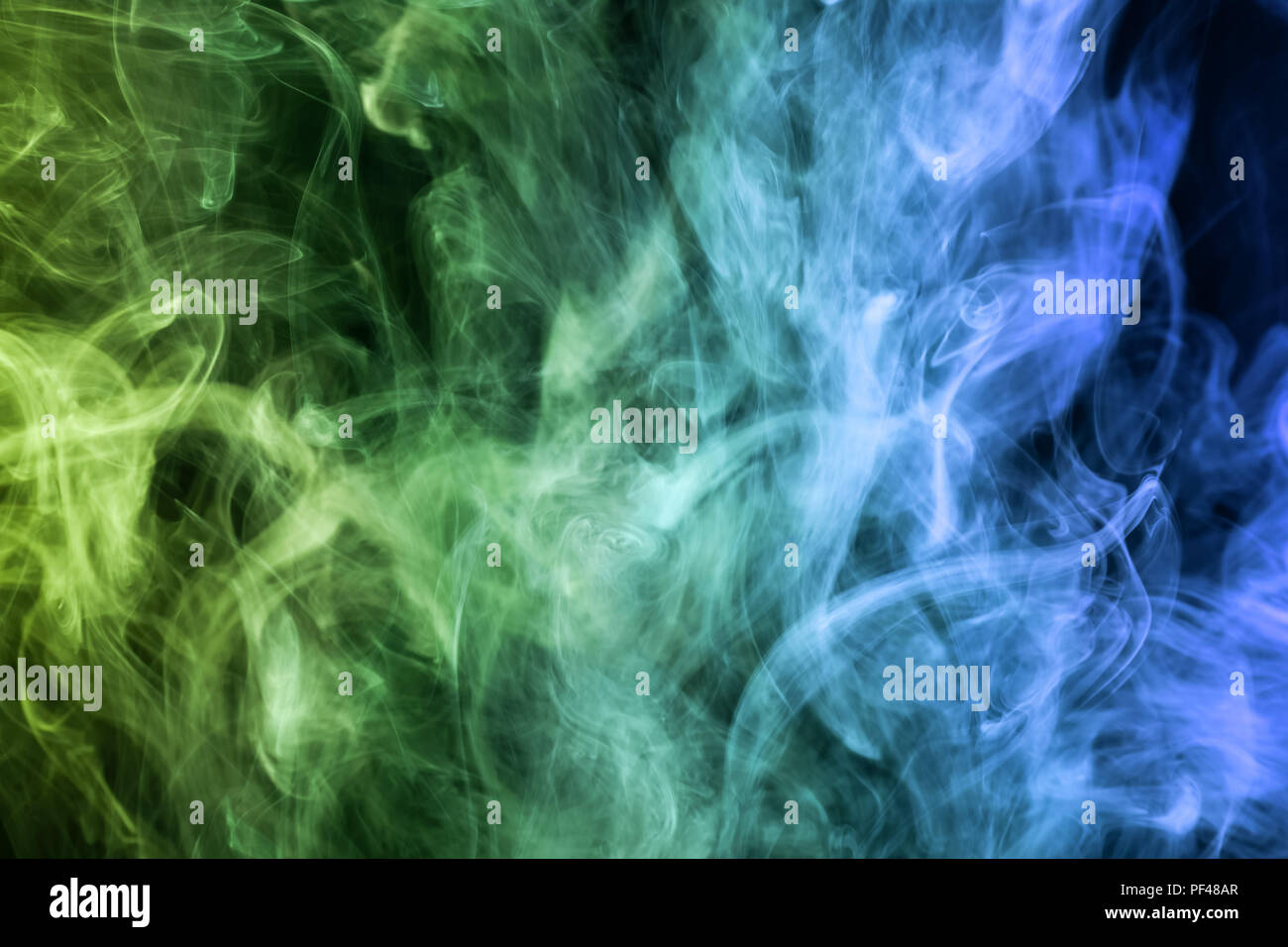 Colorful green and blue smoke on a black isolated background ...