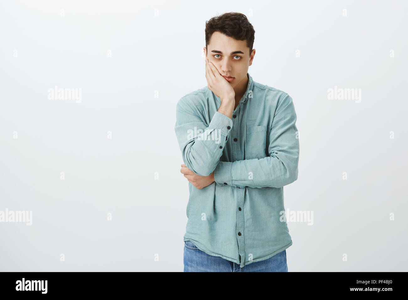 Portrait of bored pissed attractive male student in shirt, leaning face ...