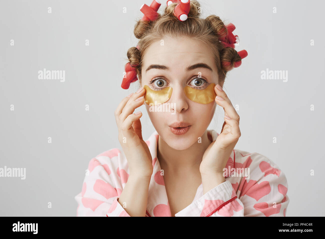 Funny playful european girl in hair-curlers, nightwear and eye patch ...