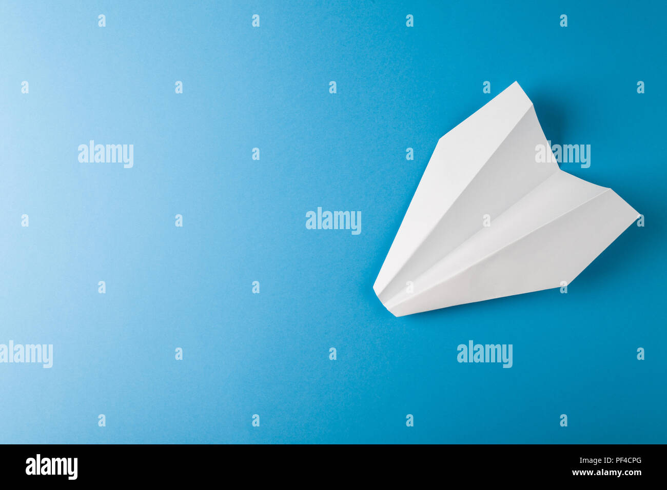 Paper airplane on a blue paper background. Studio shot Stock Photo - Alamy