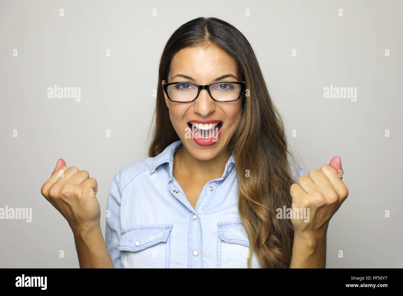 Happy successful young woman with raised hands shouting and celebrating ...