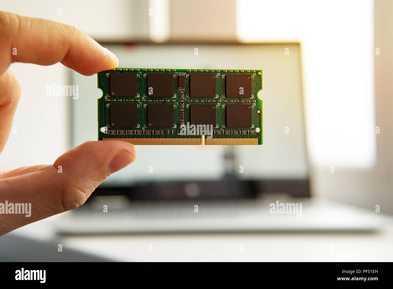 Hand with memory on a computer motherboard. RAM in hand on the ...