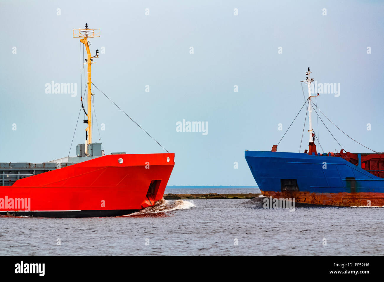 Orange cargo ship sailing past the blue bulk carrier Stock Photo - Alamy