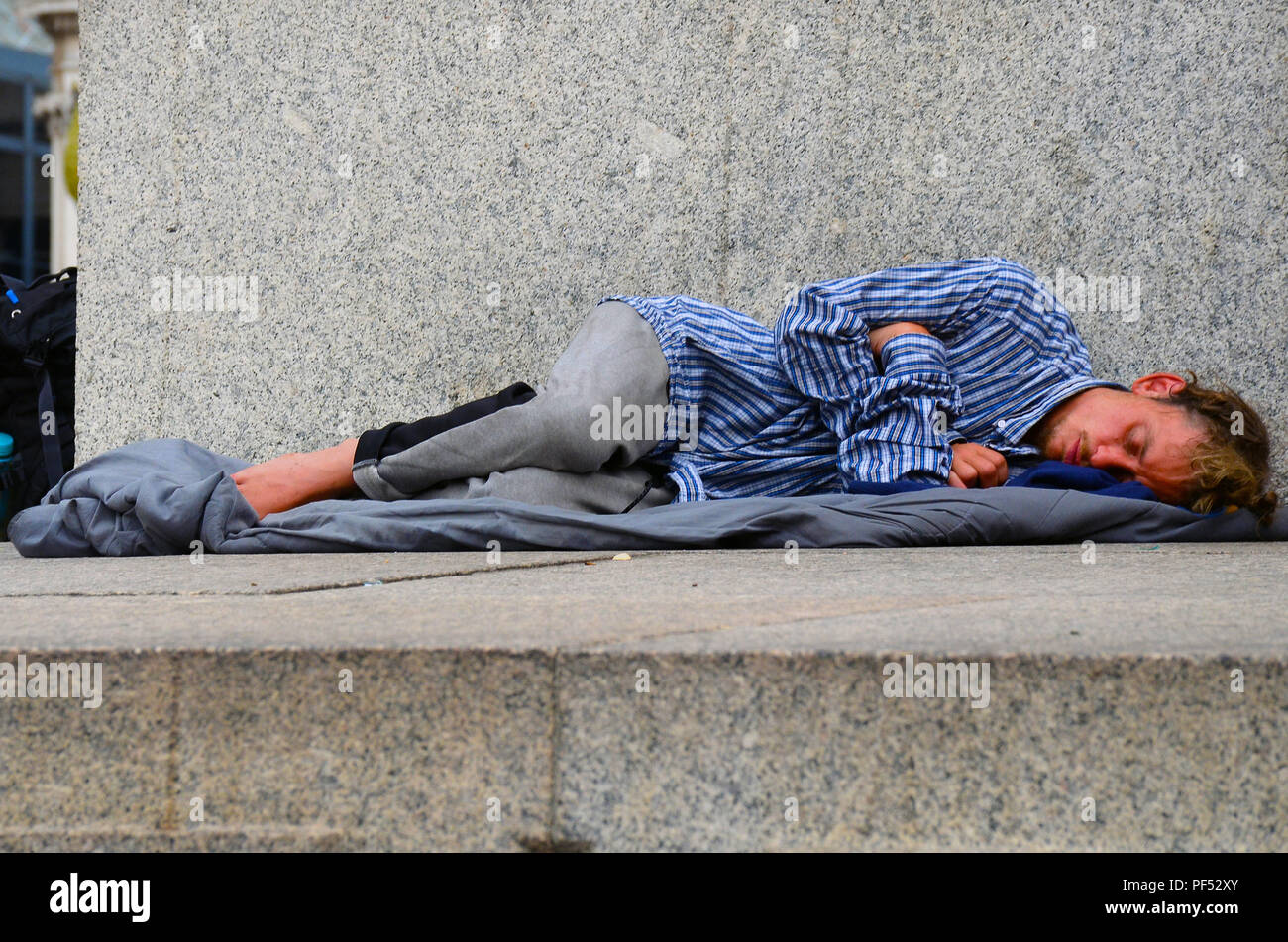 London, UK, 7 August 2018 Homeless man sleeping on the base of Nelson's ...