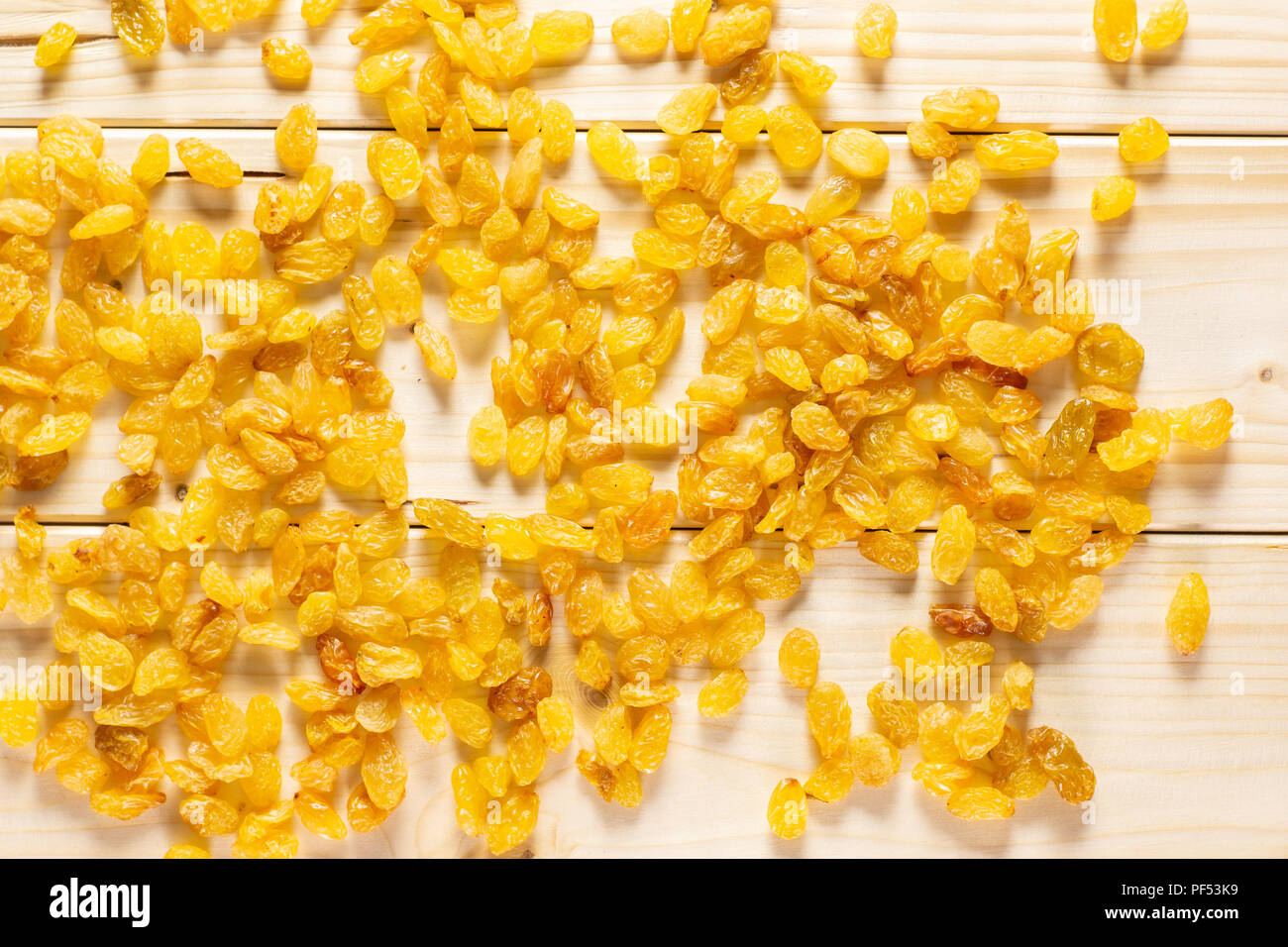 Lot of whole dry golden raisins sultana variety flatlay on natural wood ...