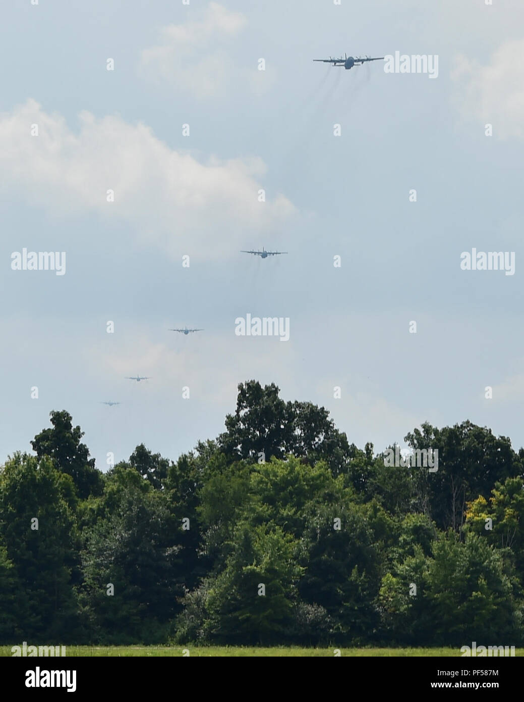 Five C-130H Hercules emerge over the tree line at Camp Ravenna’s drop ...