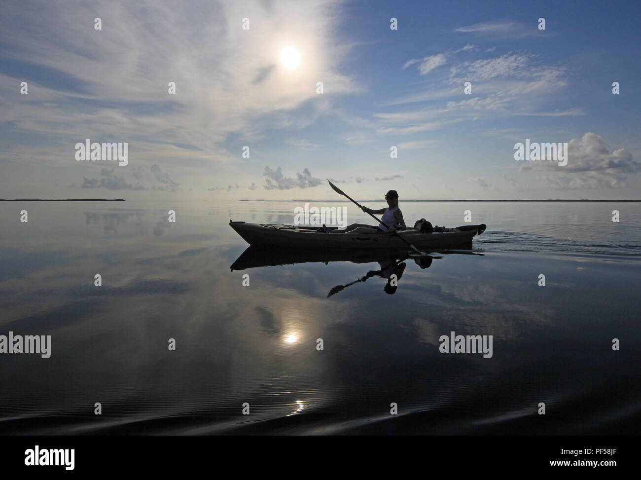 Woman kayaking on an exceptionally calm day with wonderful cloud ...